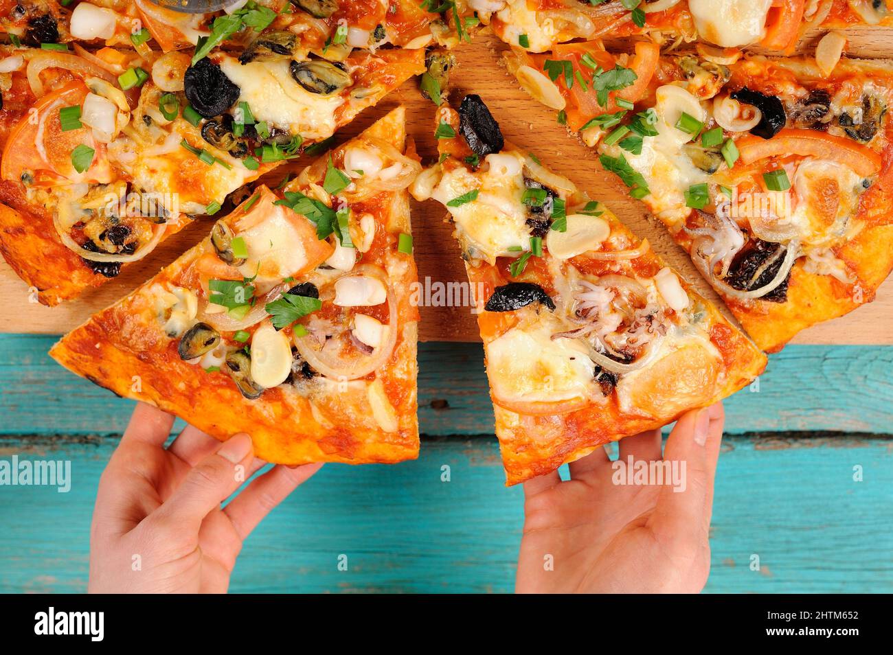 Homemade pizza with sea food in woman's hands on turquoise table ...