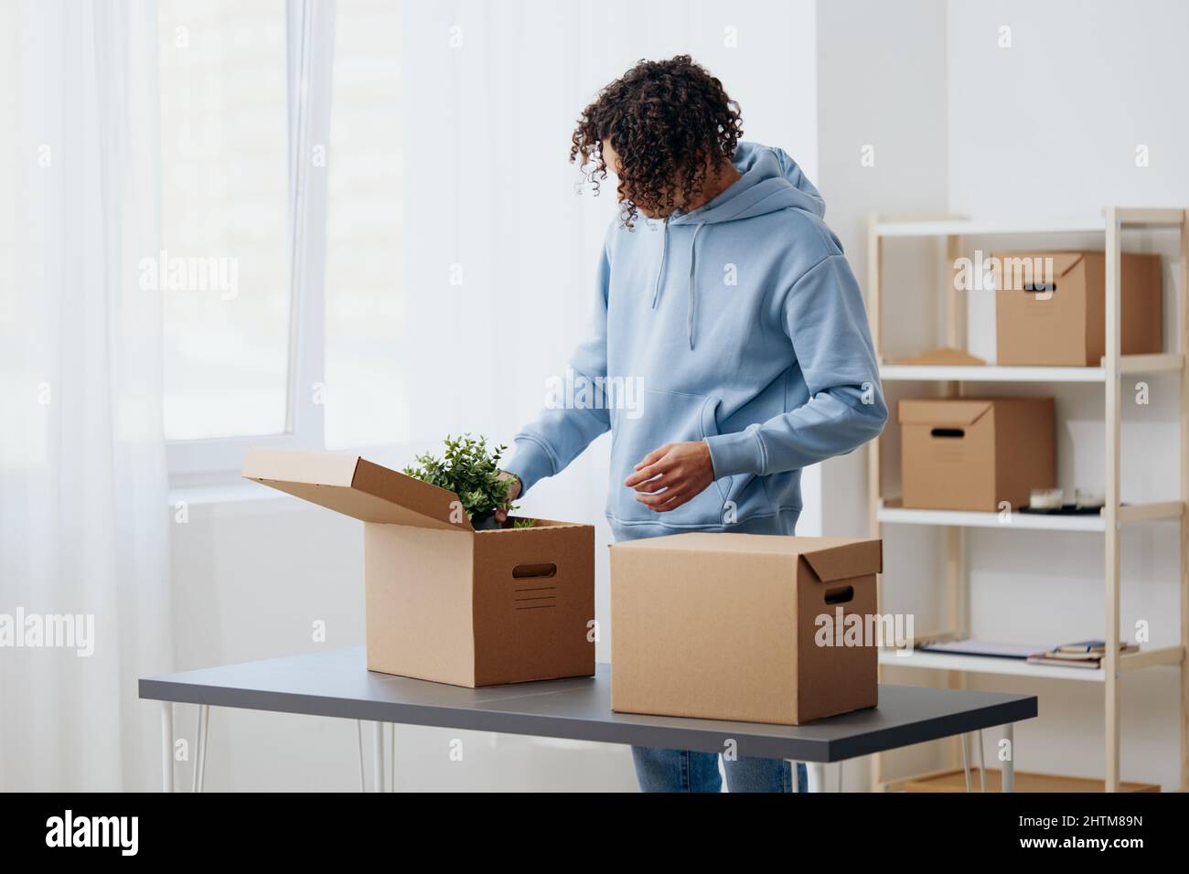 guy with curly hair unpacking things from boxes in the room sorting ...