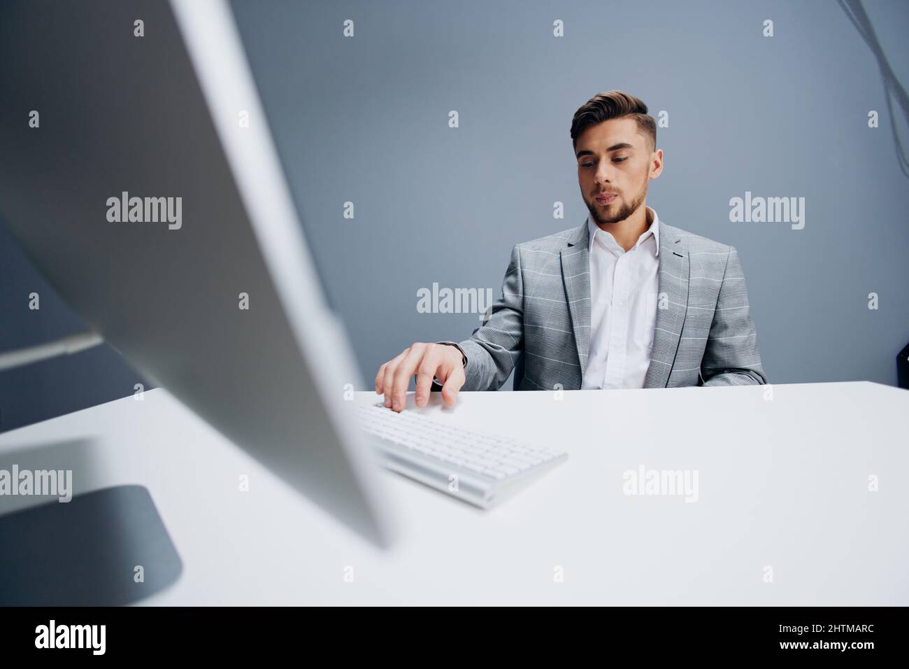 manager in a gray suit sits in front of a computer technologies Stock ...