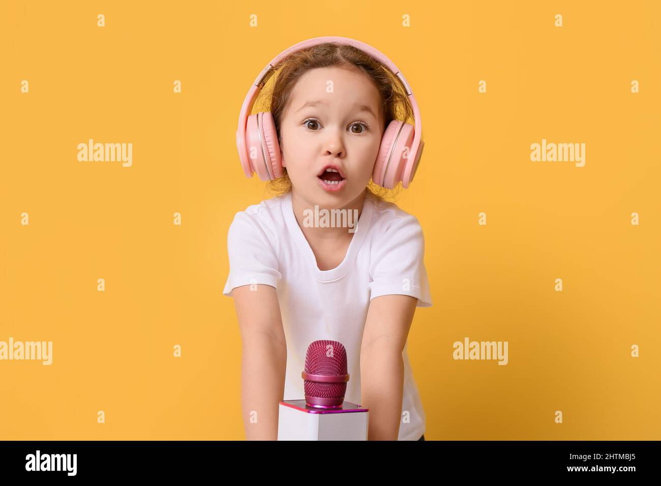Shocked little girl with microphone on color background Stock Photo - Alamy