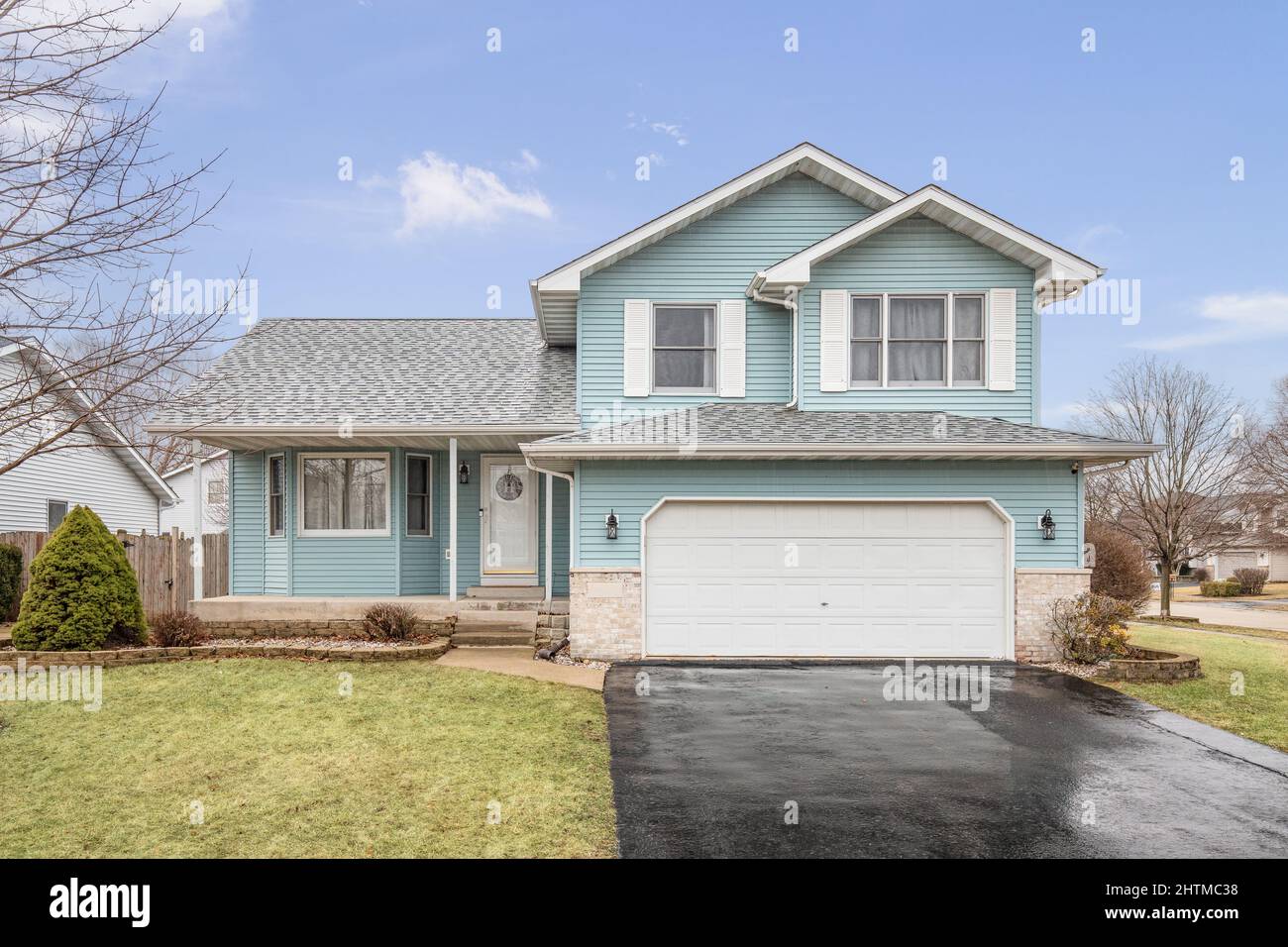 Exterior of a suburban home with a light blue siding and white shutters ...