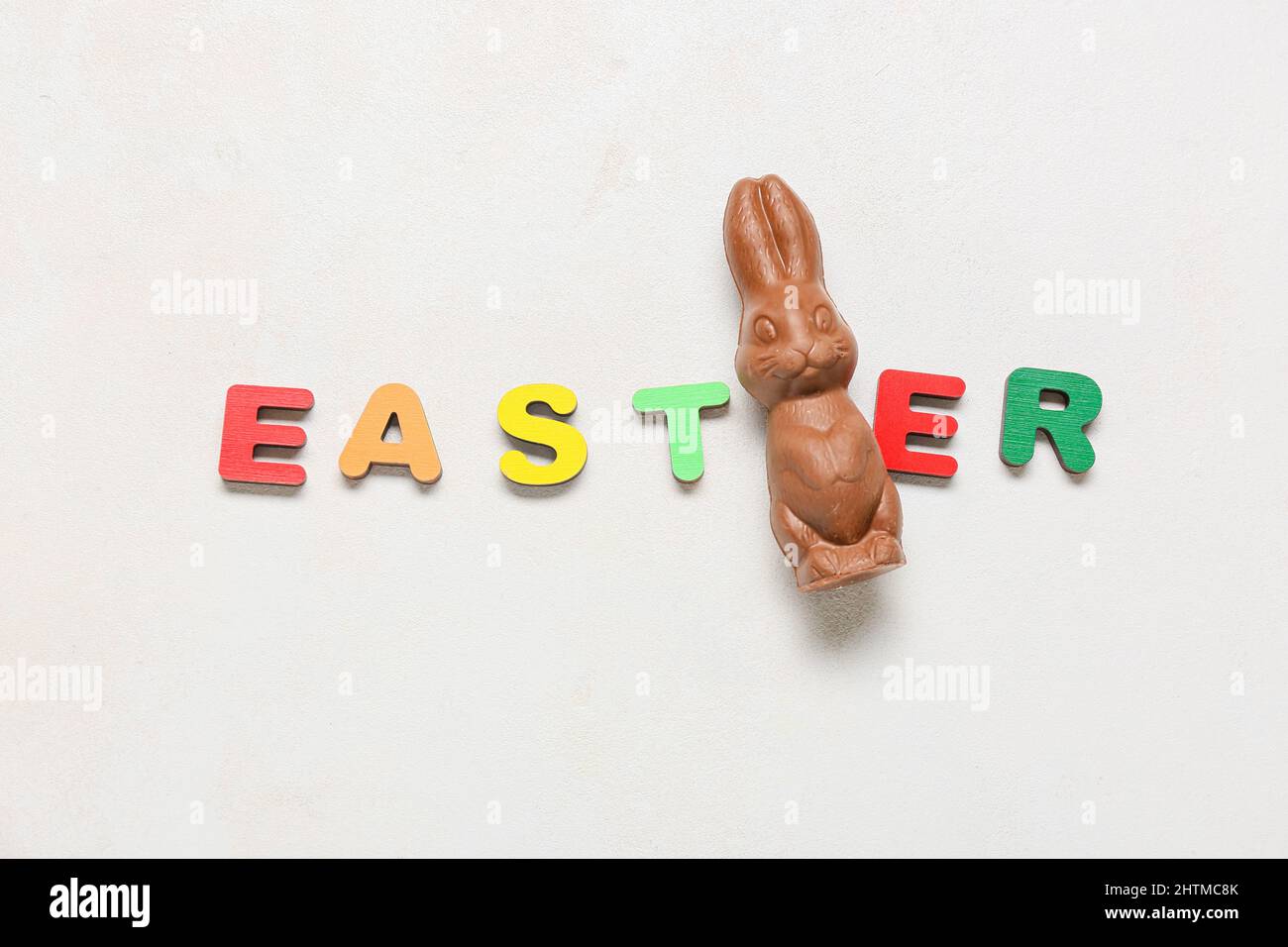 Word EASTER made of colorful letters and chocolate bunny on light ...