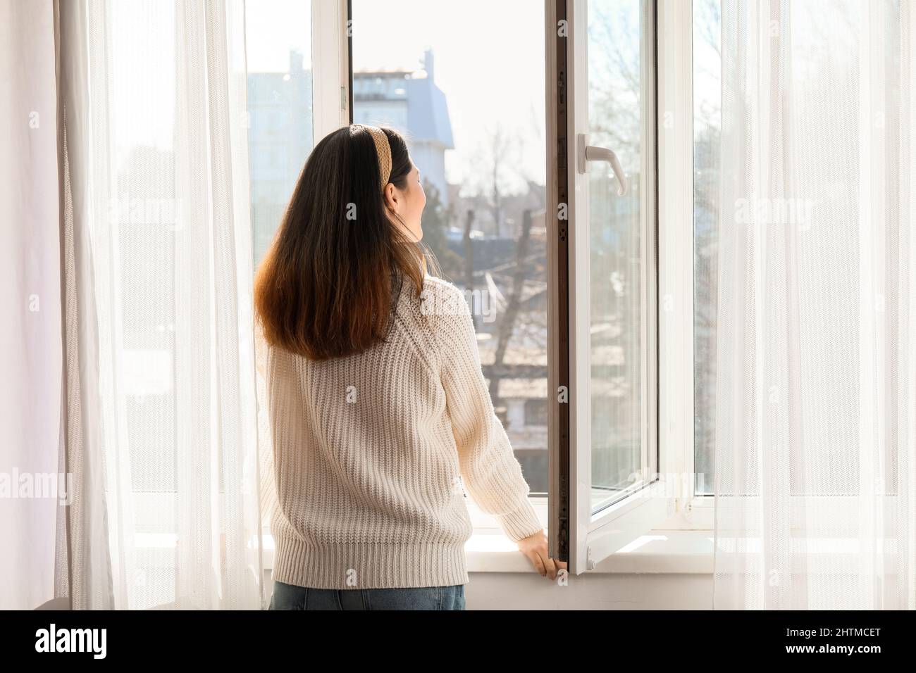 Pretty young Asian woman near open window at home Stock Photo - Alamy