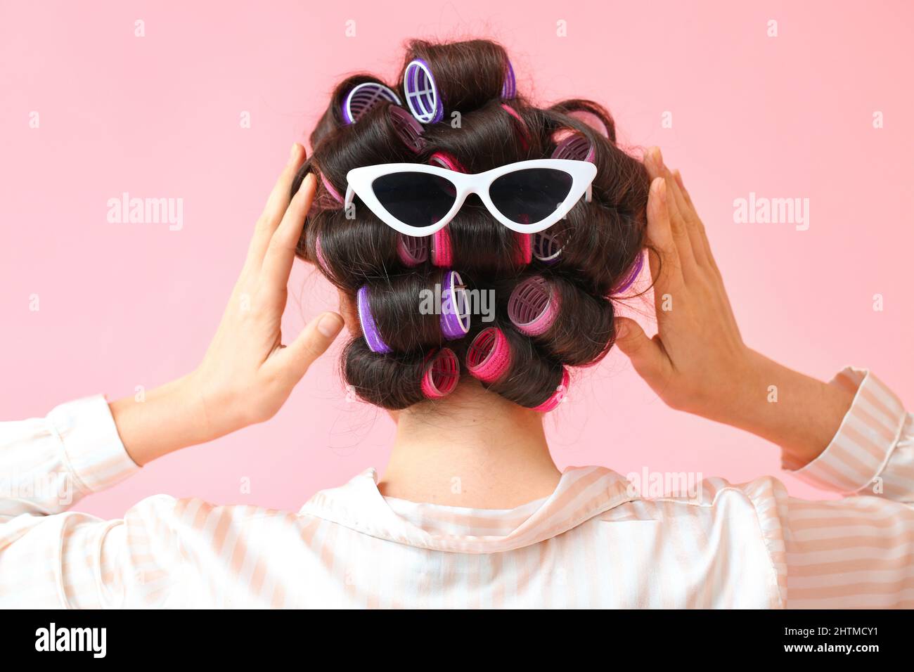 Beautiful young woman in pajamas, hair curlers and with sunglasses on ...