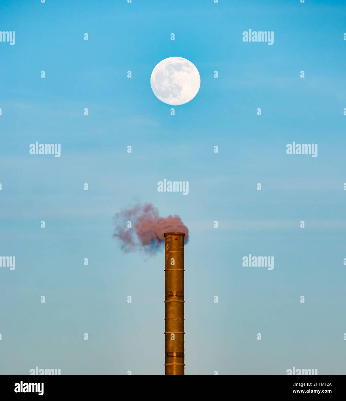 Full moon rising over industrial cooling tower with steam at dusk ...