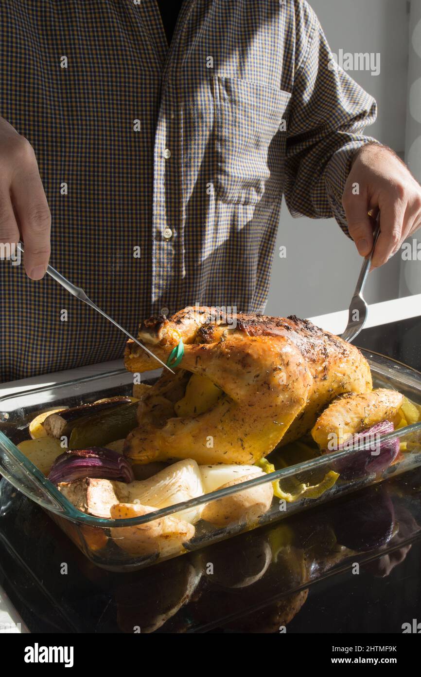 Unrecognizable man preparing a juicy oven baked chicken with vegetables ...
