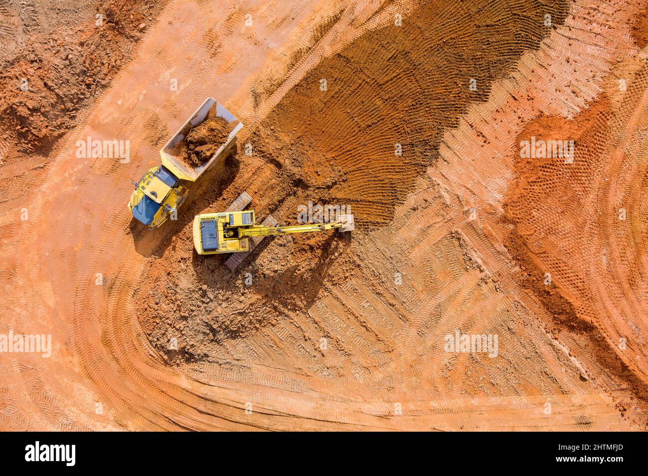 Bulldozer is scraping a layer of soil and excavator is digging and ...
