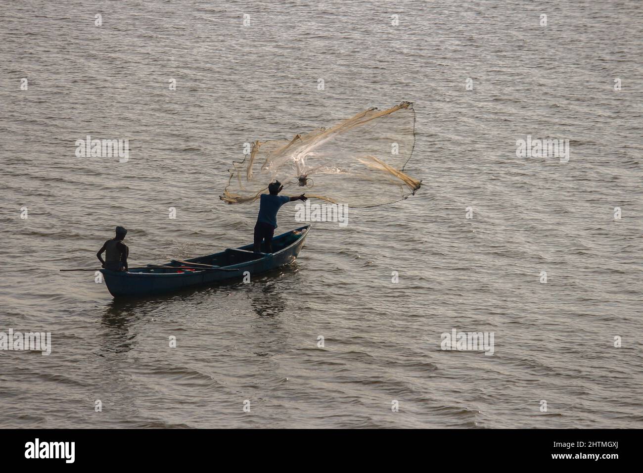Person throwing the fishing net in the water from a boat Stock Photo ...
