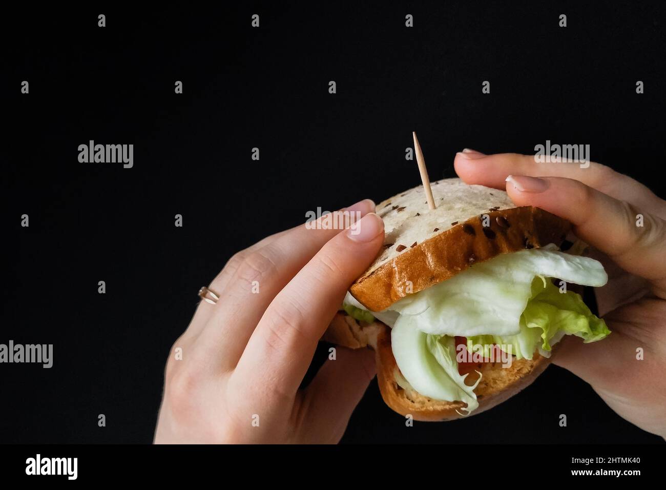 A hand holding a sandwich in the hand and isolated in a black ...