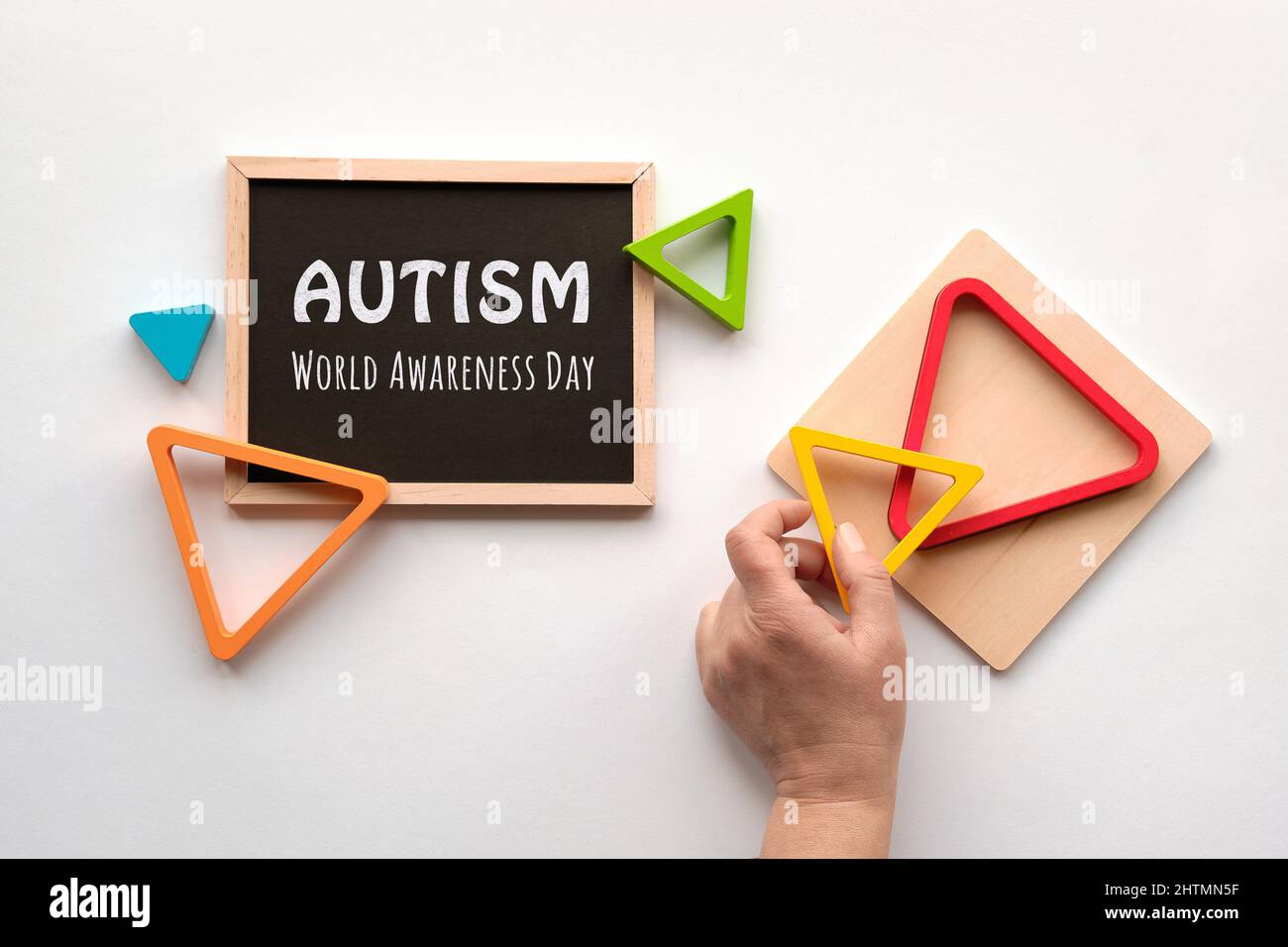 Text Autism awareness month on blackboard. Nested wood triangles in ...