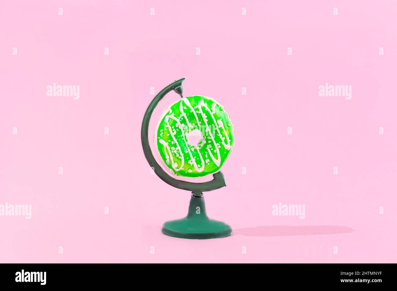 A globe made of a bright green donaught on a dark green stand. Pink ...