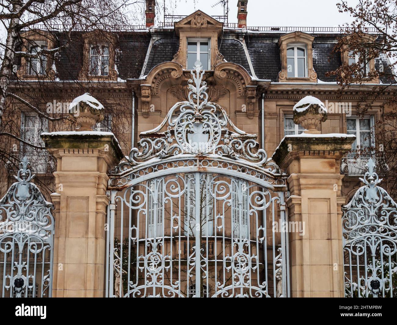 An old manor with beautiful gates is covered with snow. Strasbourg ...