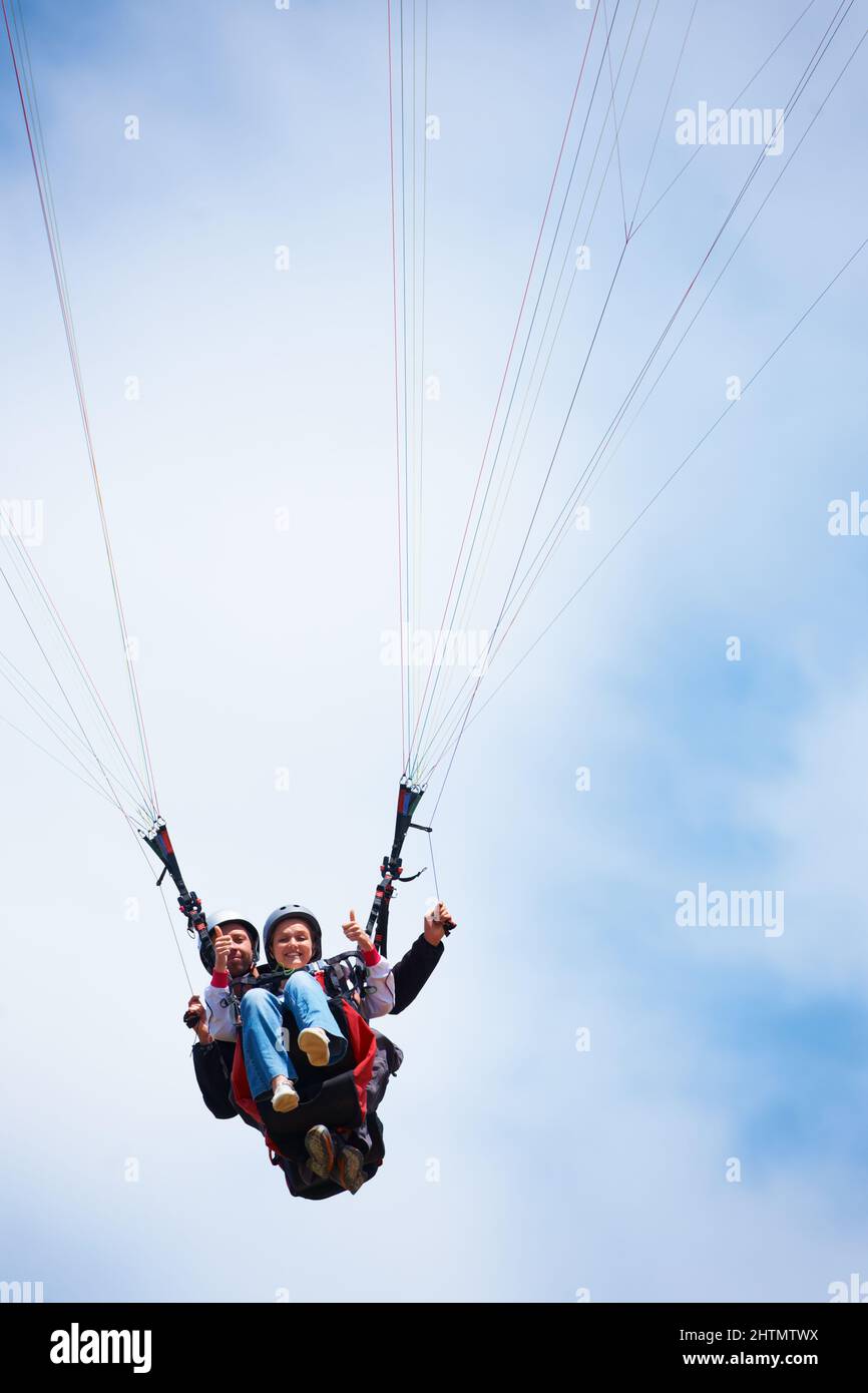 Thumbs up for paragliding. Low angle shot of two people tandem ...