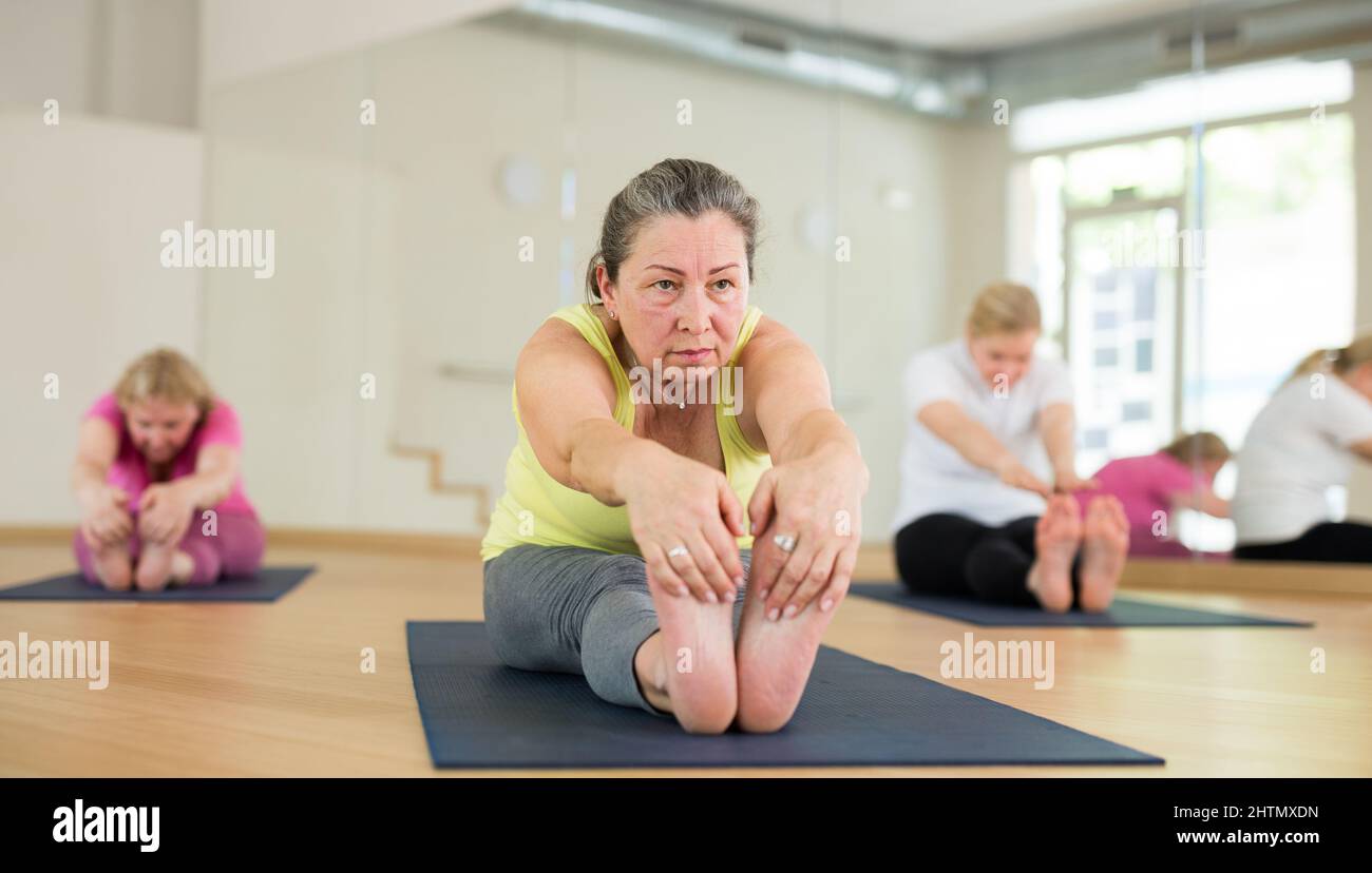 Women practicing yoga, sitting in Seated forward bend exercise ...
