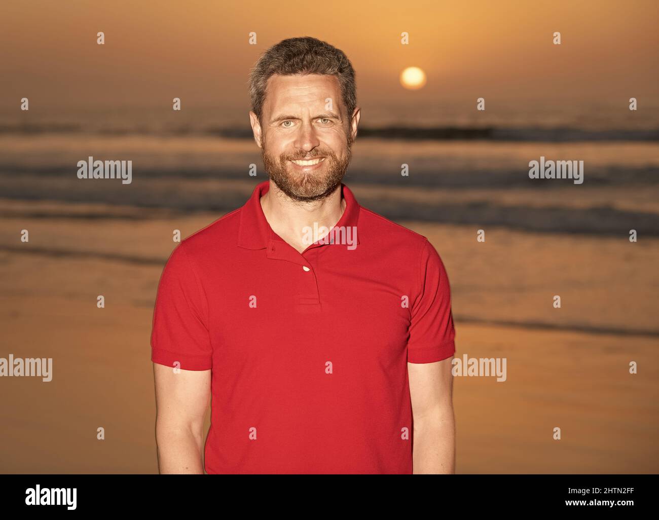 cheerful man with beard in sunset over sea. happy unshaven guy on beach ...