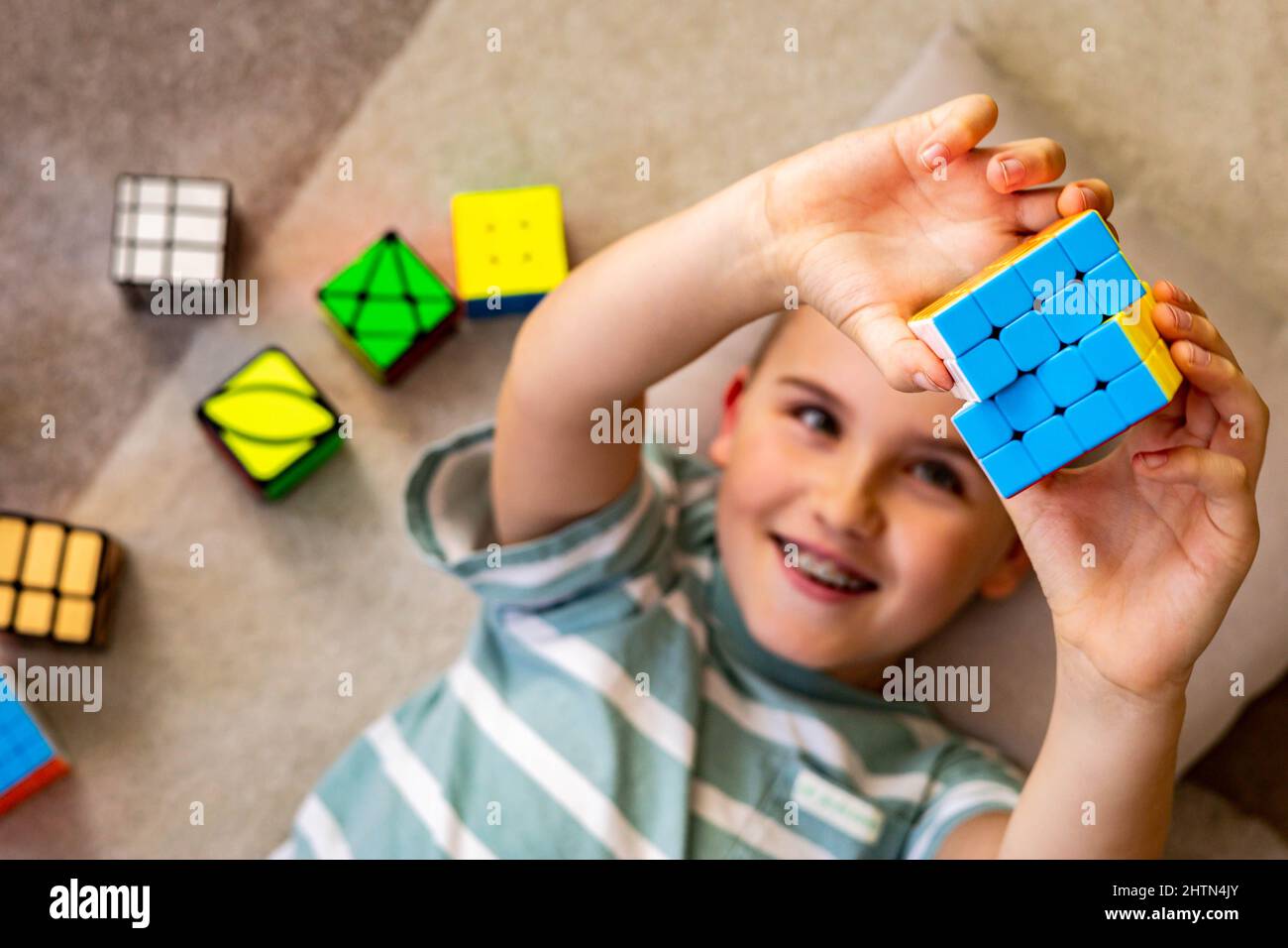 Top view happy male kid assembling multicolored mind logical toy Rubik ...