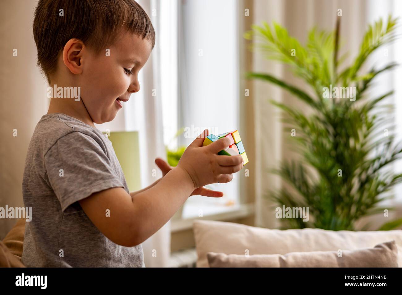 Cute baby boy assembling multicolored Rubik's cube solving logical game ...