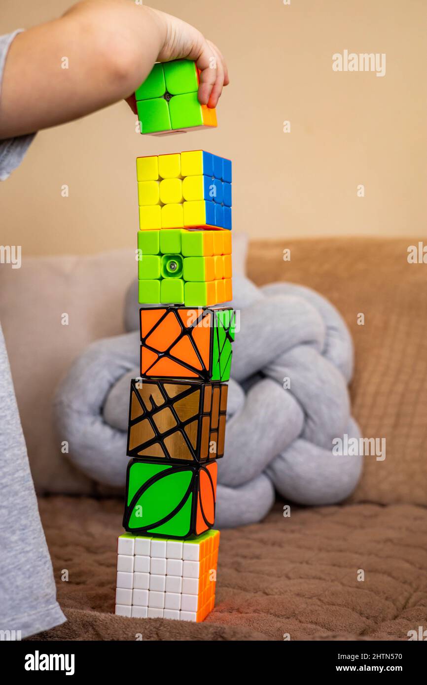 Closeup cute baby boy hands building Rubik's cubes tower having fun ...