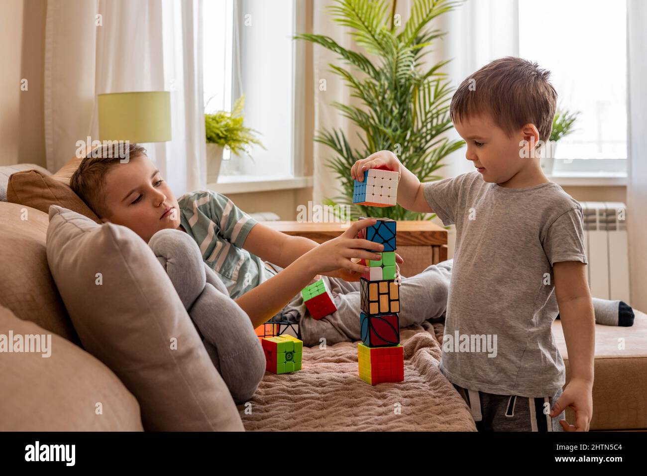 Funny male kids building tower from different Rubik's cubes playing ...