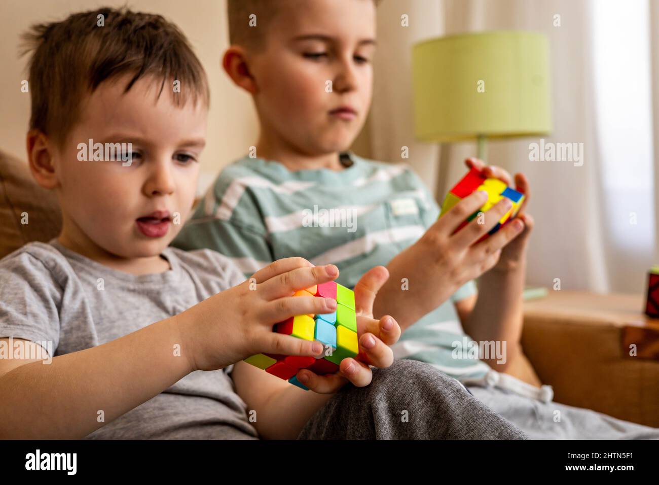 Two male kids brothers assembling Rubik's cube thinking solving logic ...