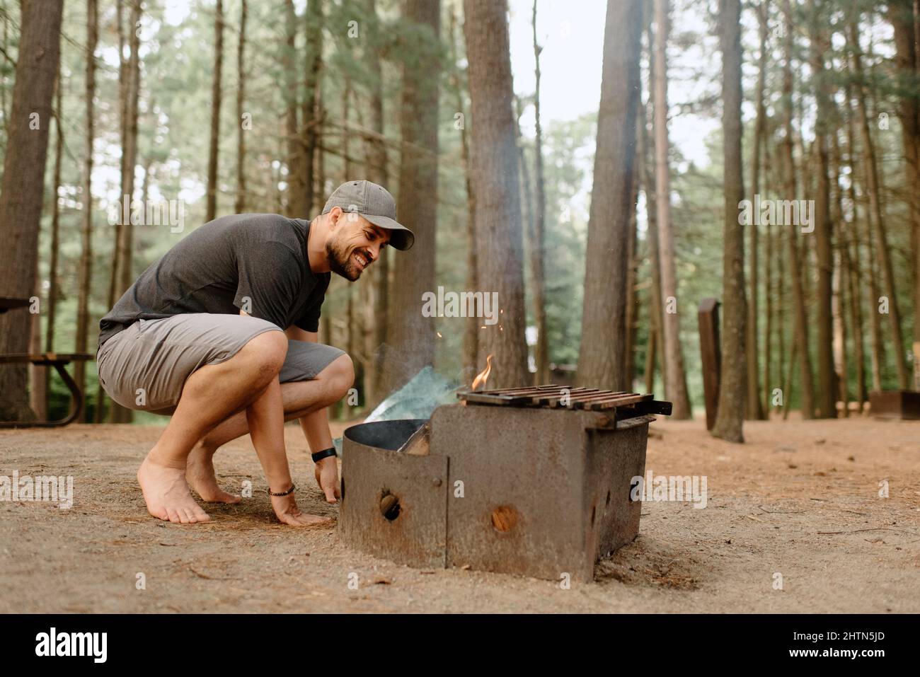 Canada, Yukon, Whitehorse, Man making fire on fire pit in campsite ...