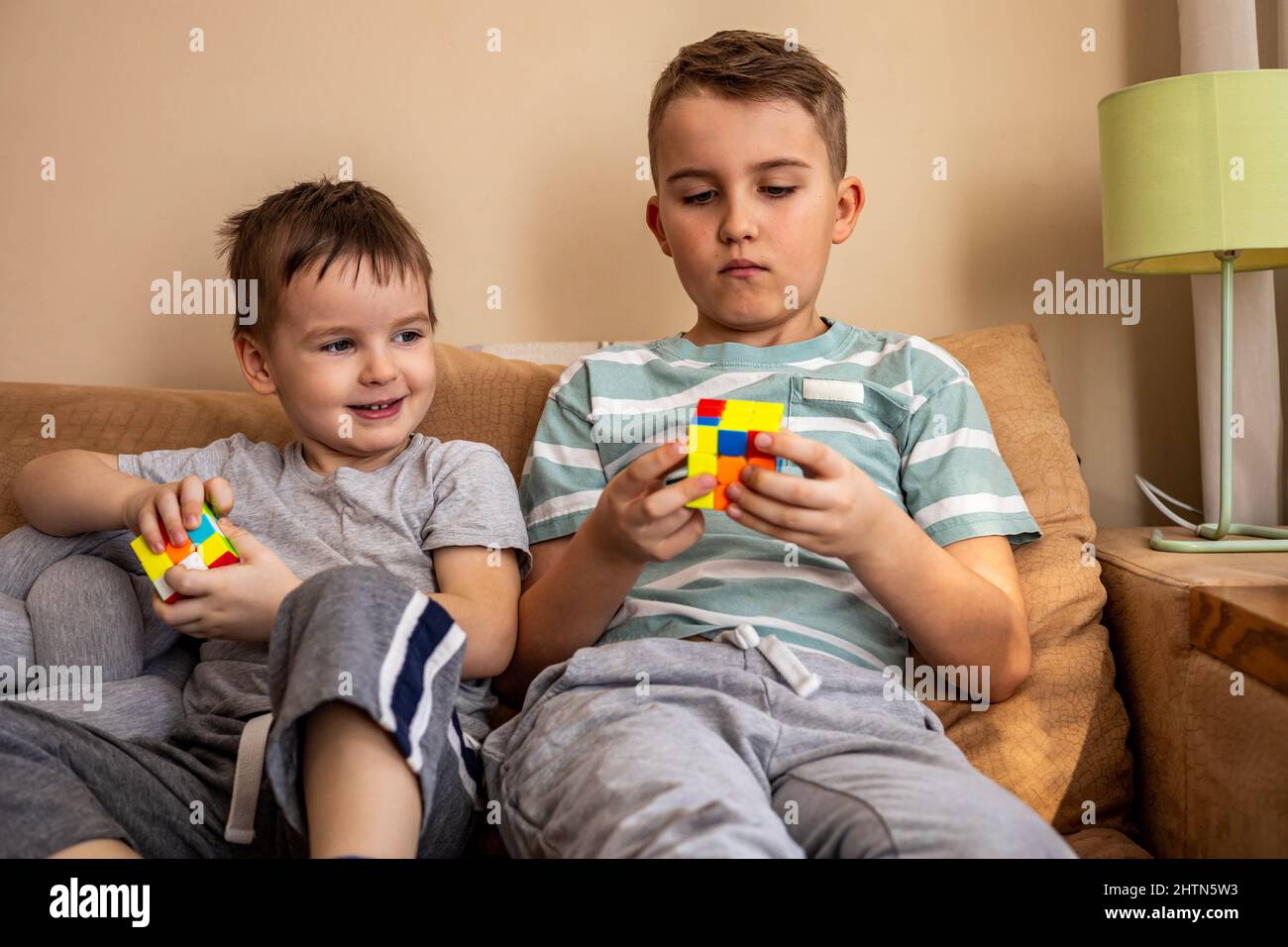 Two male kids brothers assembling Rubik's cube thinking solving logic ...