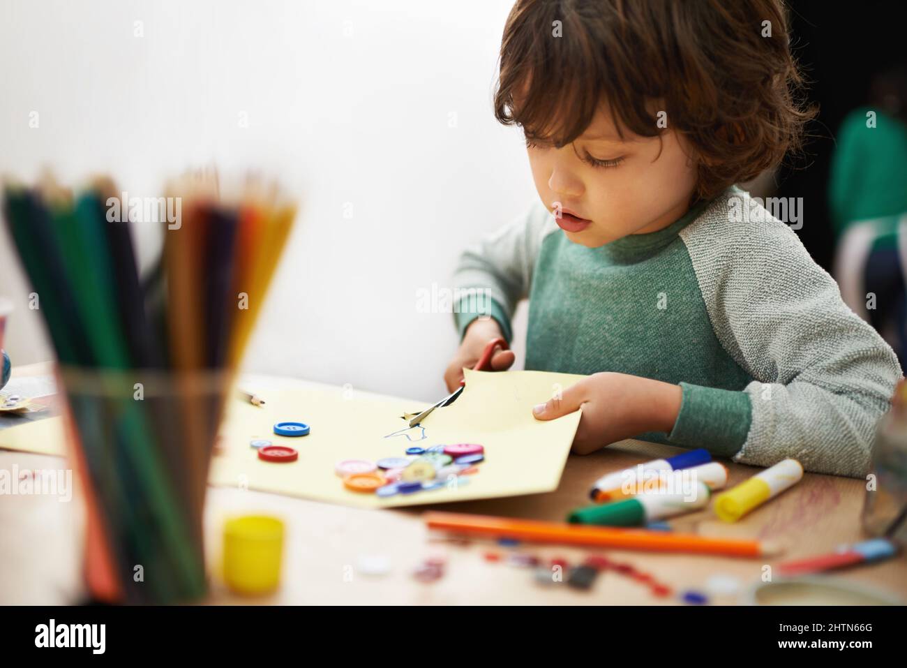 Getting creative with cutting. A cute little boy doing crafts at pre ...