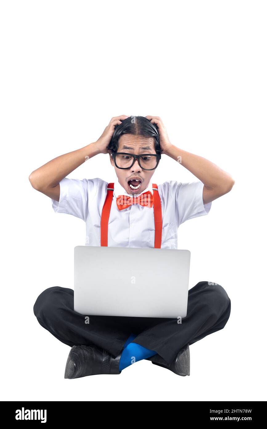 Asian nerd with ugly face sitting while using a laptop with shocked ...
