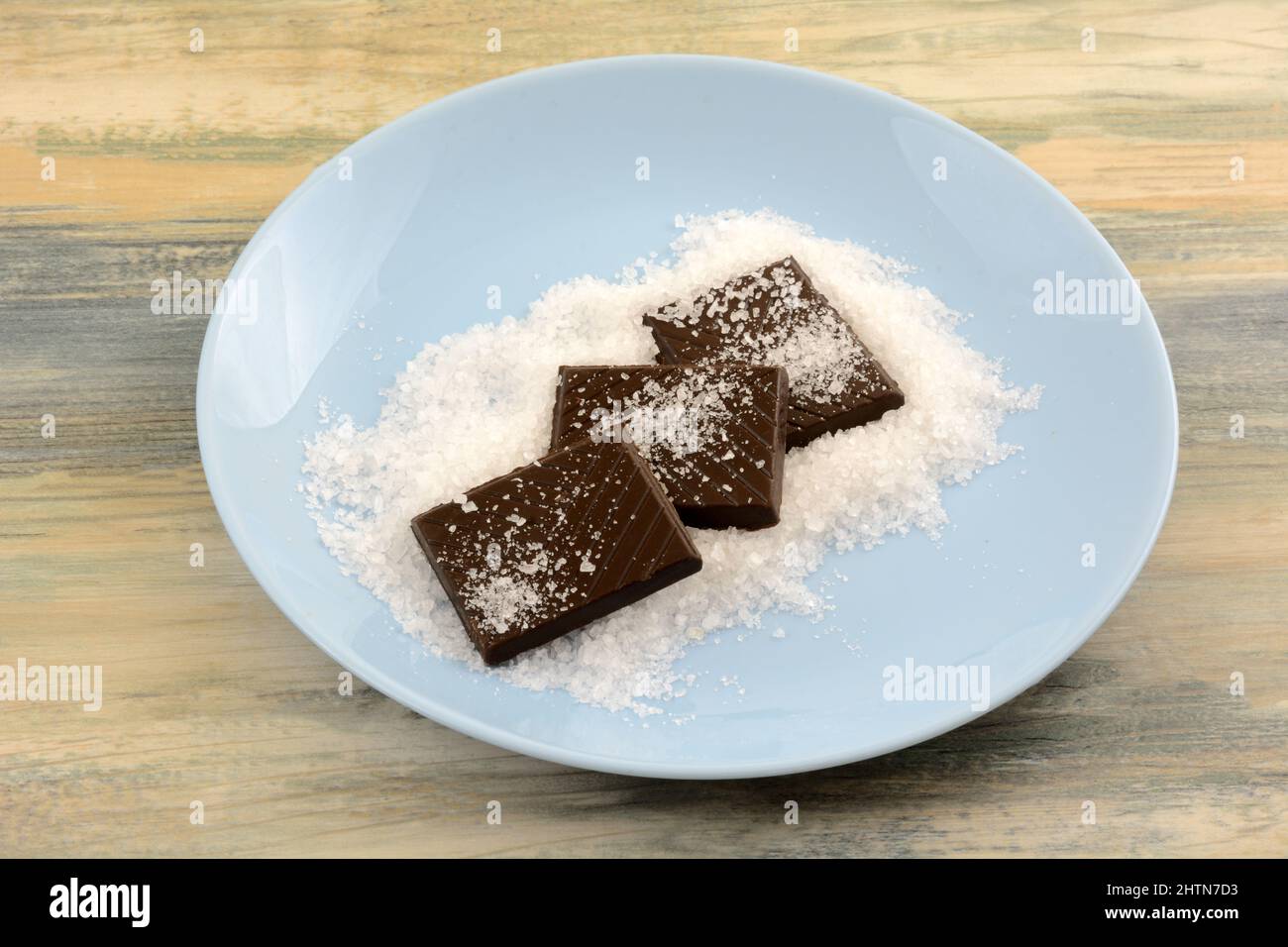 Dark chocolate candy bar square pieces with sea salt on blue snack ...