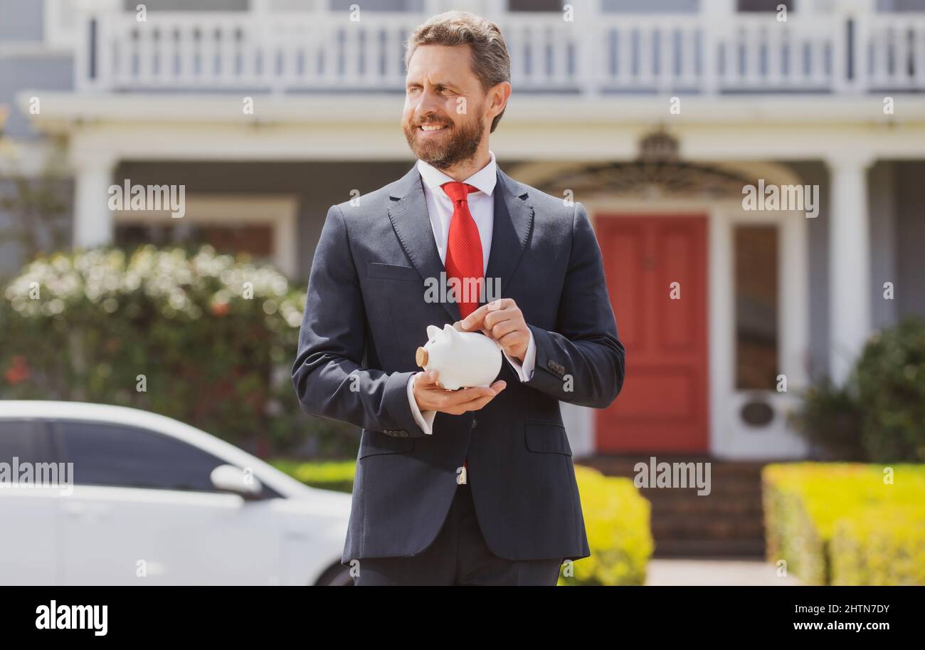 Businessman putting money in piggy bank on home background. Handsome ...