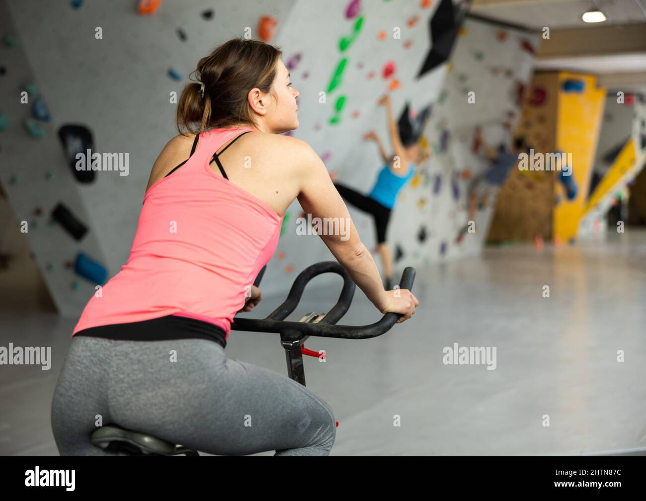 Rear view of woman riding exercise bike in climbing center Stock Photo ...