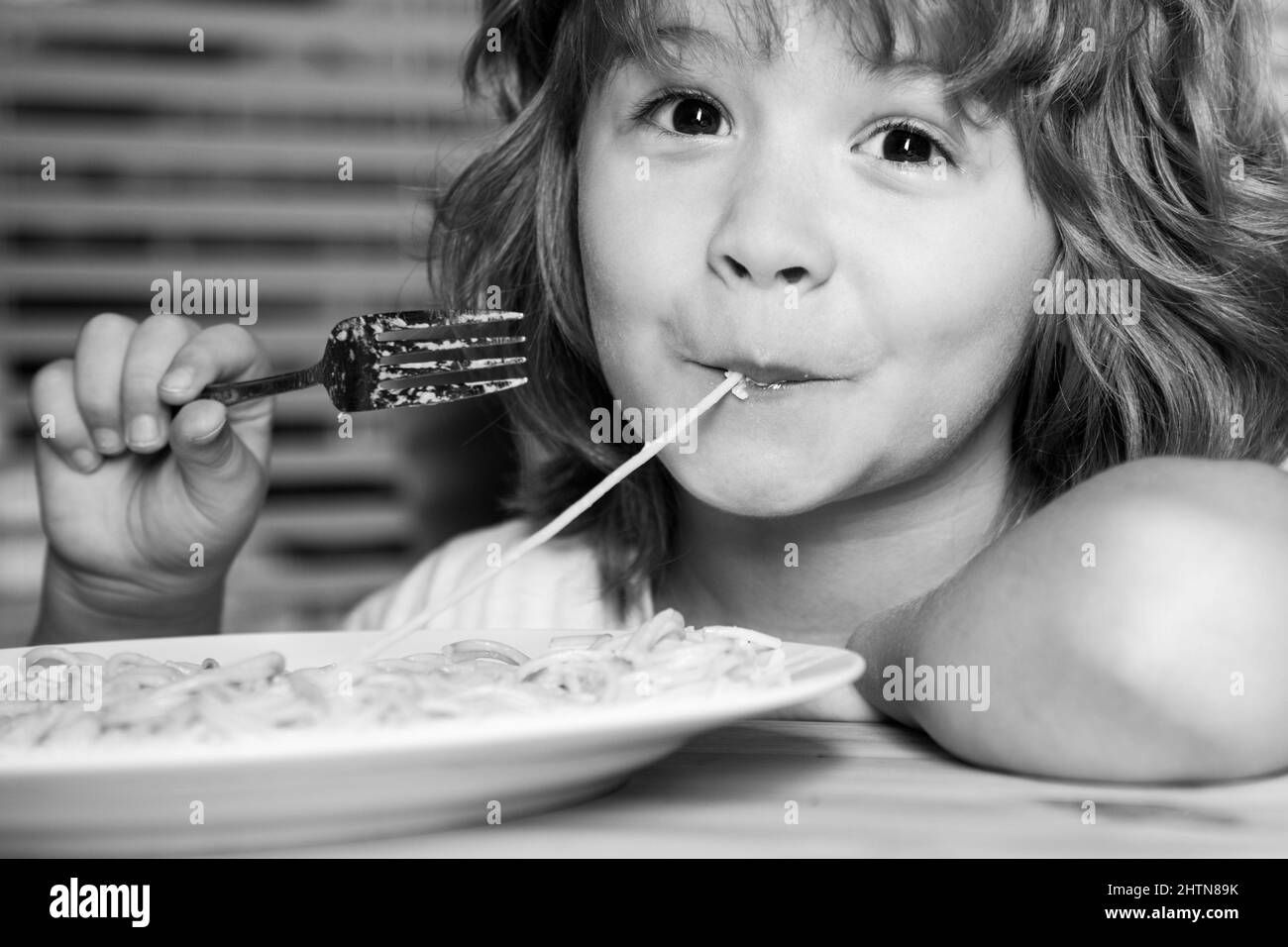 Portrait of a cute child boy eating pasta, spaghetti. Close up ...