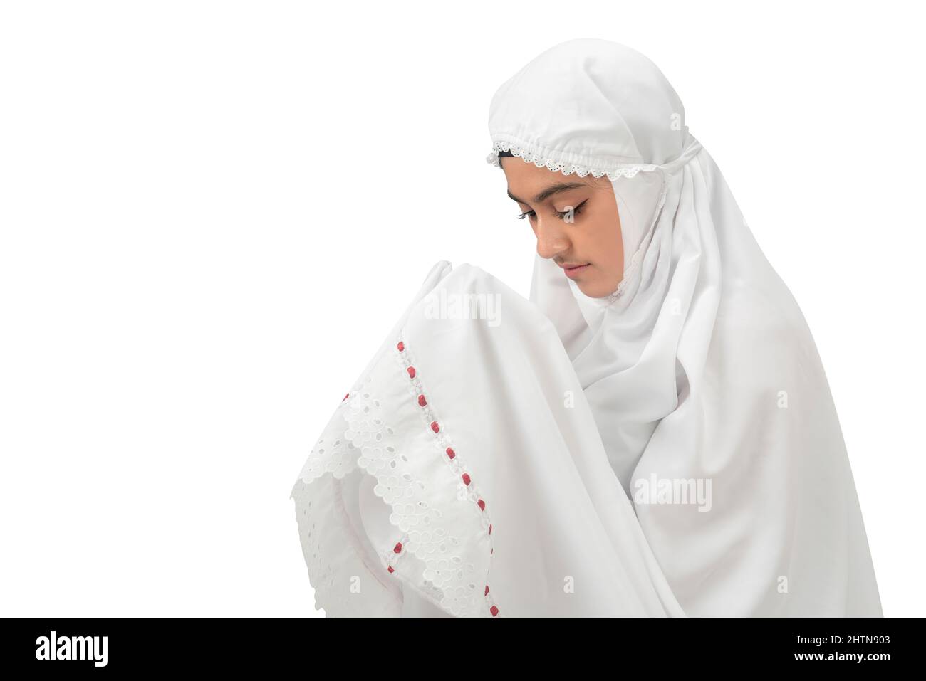 Asian Muslim woman in a veil standing while raised hands and praying ...