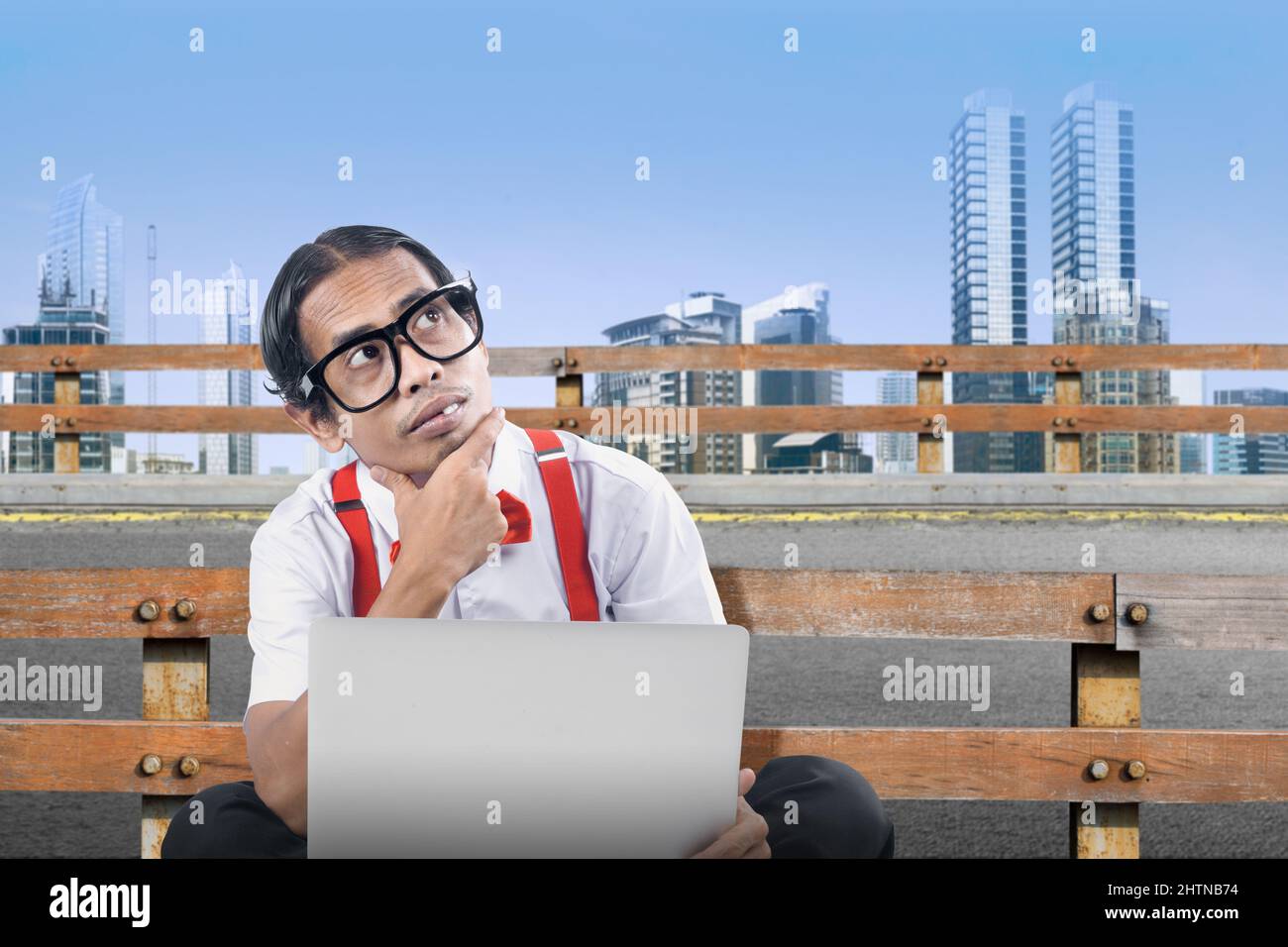 Asian nerd with ugly face sitting while using a laptop and thinking ...