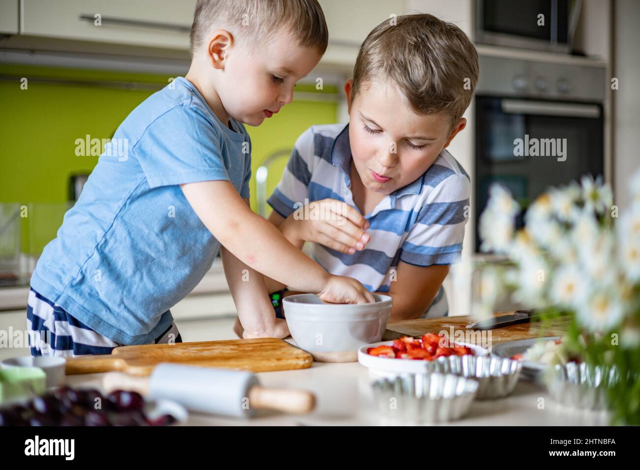 Funny brother male kids rejoicing having fun cooking summer dessert ...
