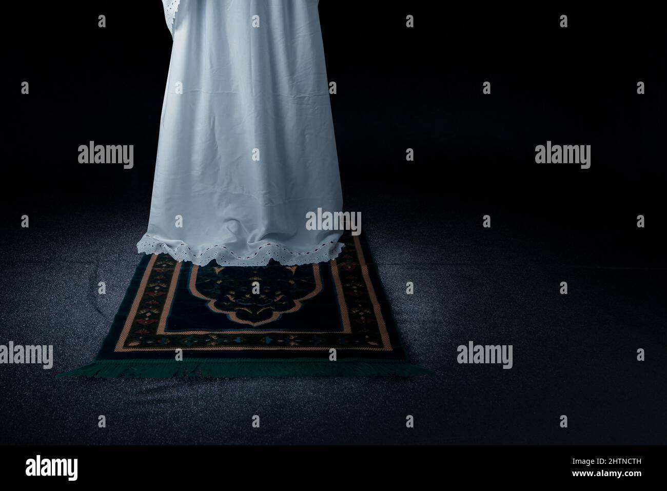 Muslim woman in veil in praying position (salat) on the prayer rug with ...