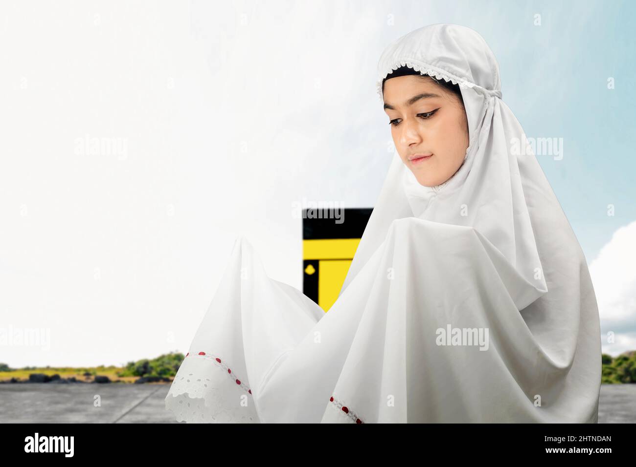 Asian Muslim woman in a veil standing while raised hands and praying ...