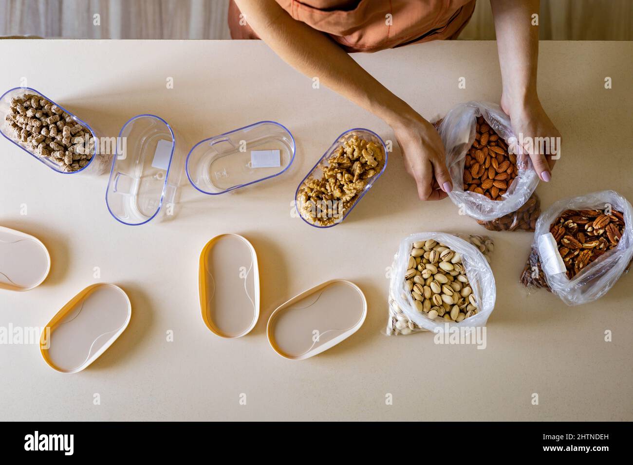 Closeup housewife hands placing nuts plastic package into container box ...