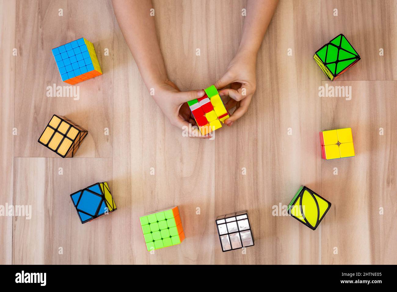 Top view male adolescent hands assembling Rubik's cubes 3x3, axis, 2x2 ...