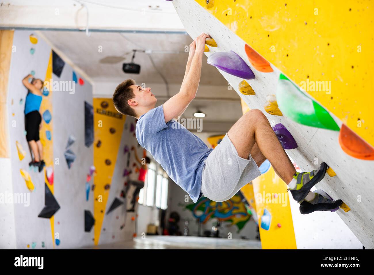 Young man climbing on rock-climbing wall Stock Photo - Alamy
