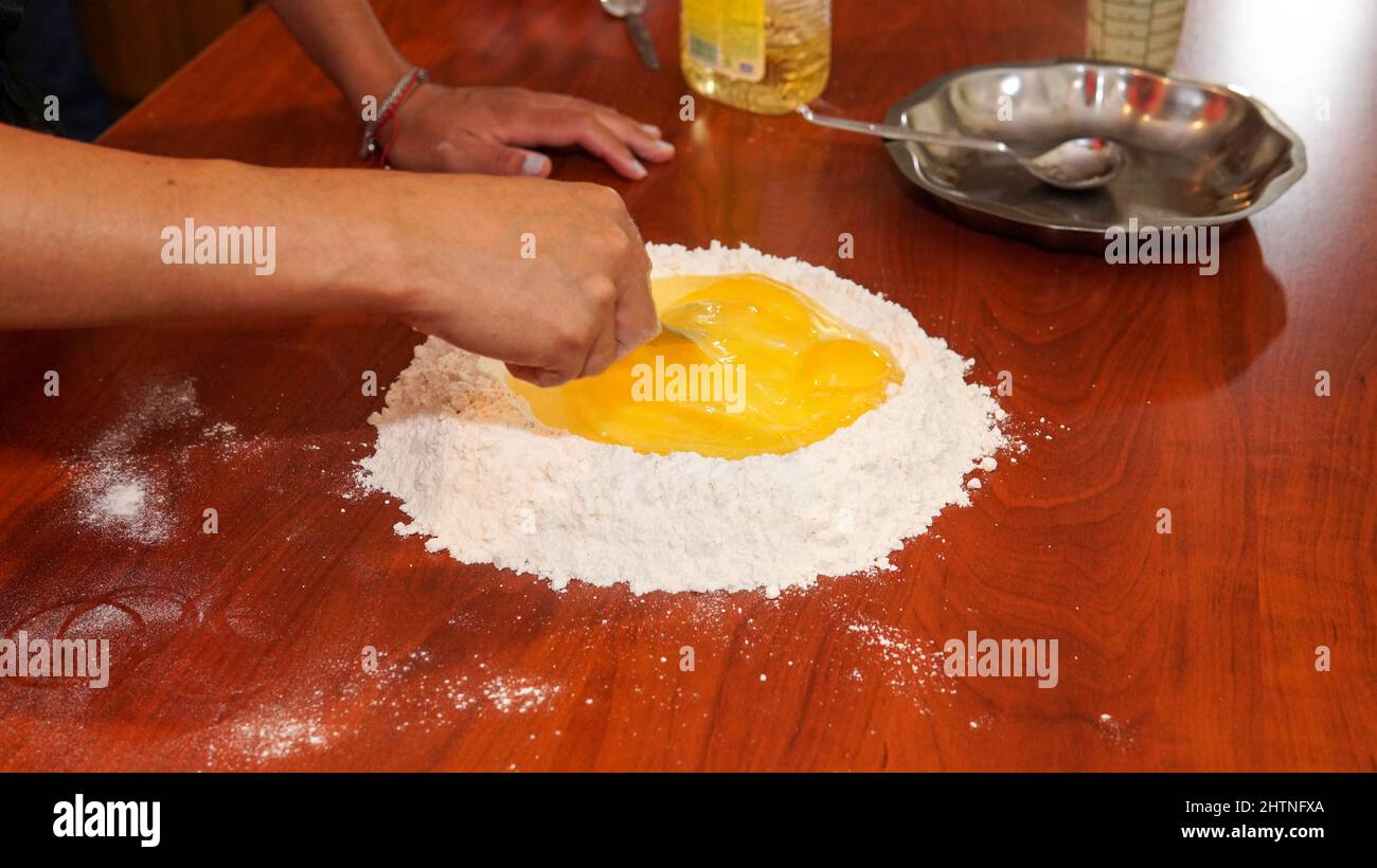 woman mixing raw eggs in a small heap of flour for making a dough Stock Photo - Alamy