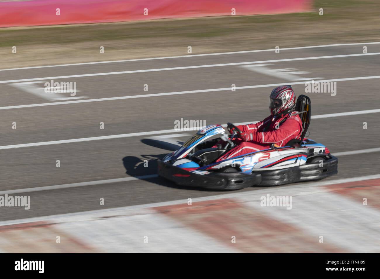 Side view of a man in helmet driving go-kart on karting circuit at ...