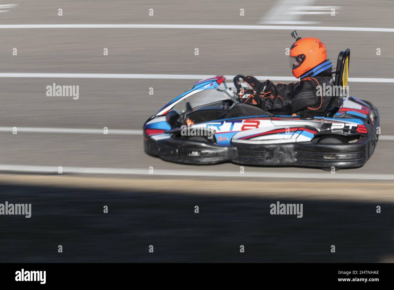 Closeup shot of a man in helmet driving go-kart on karting circuit at ...