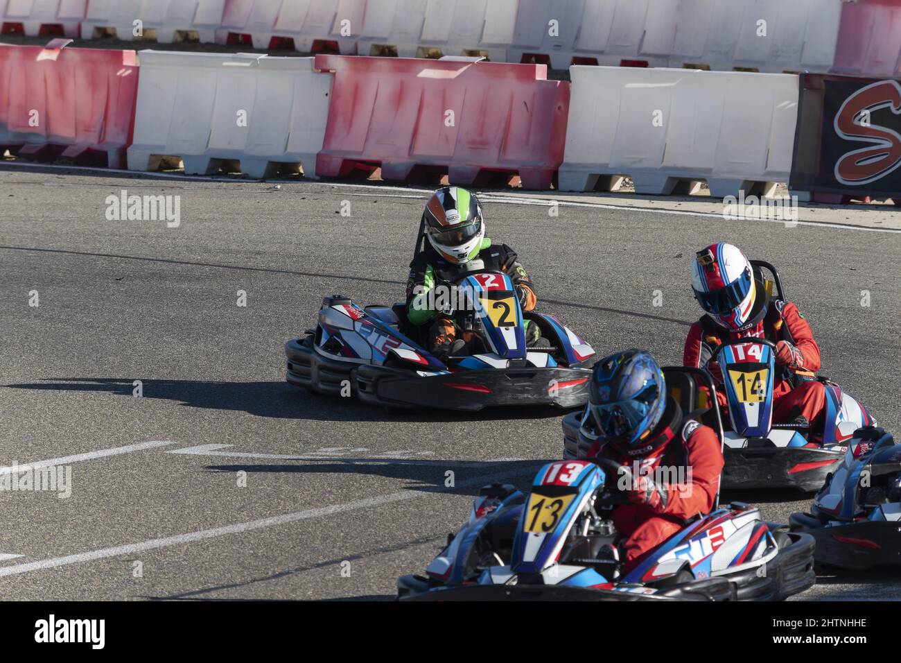 View of three men in helmet driving go-kart on karting circuit at ...