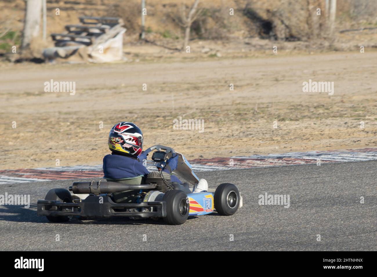 Back view of a child in helmet driving go-kart on karting circuit at ...