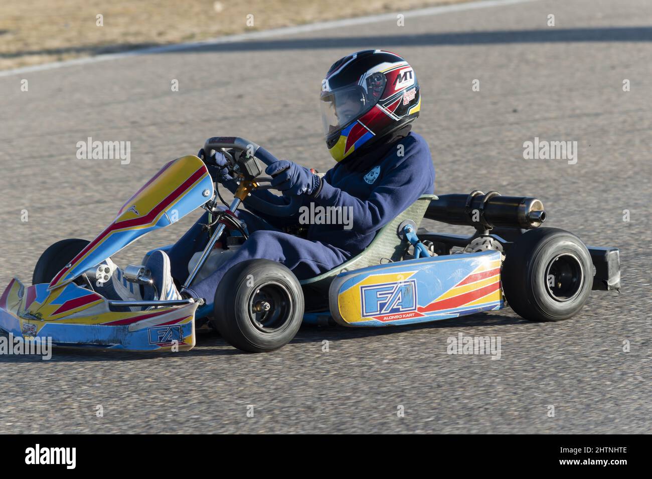 Side view of a child in helmet driving go-kart on karting circuit at ...