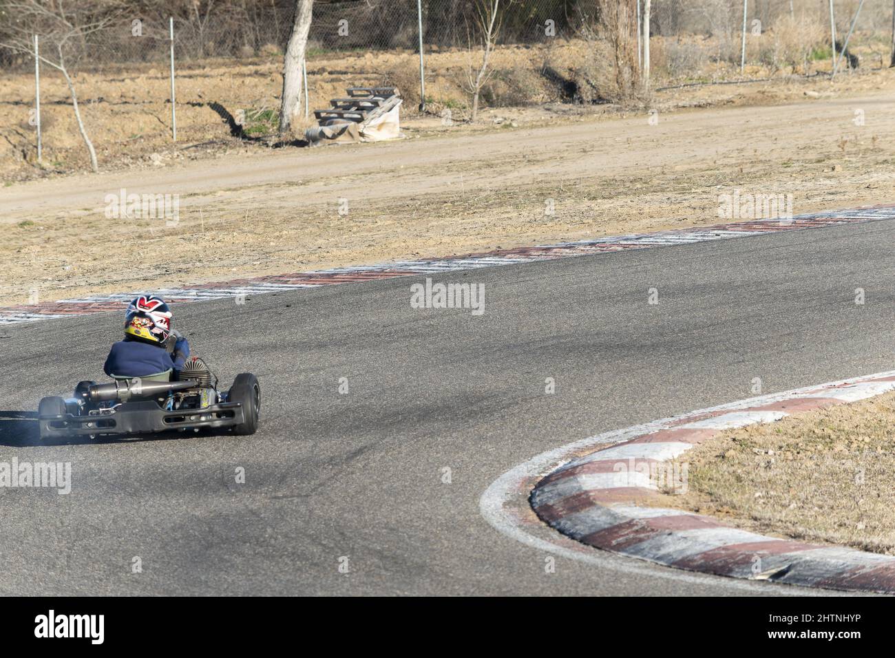 Back view of a child in helmet driving go-kart on karting circuit at ...