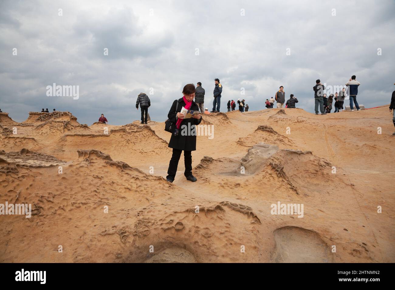 An Asian woman compares rock formations with a brochure at Yehliu ...