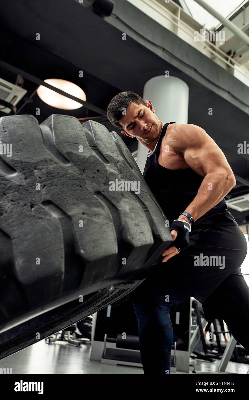 Muscular fitness man flipping tire wheel. Concept functional training ...