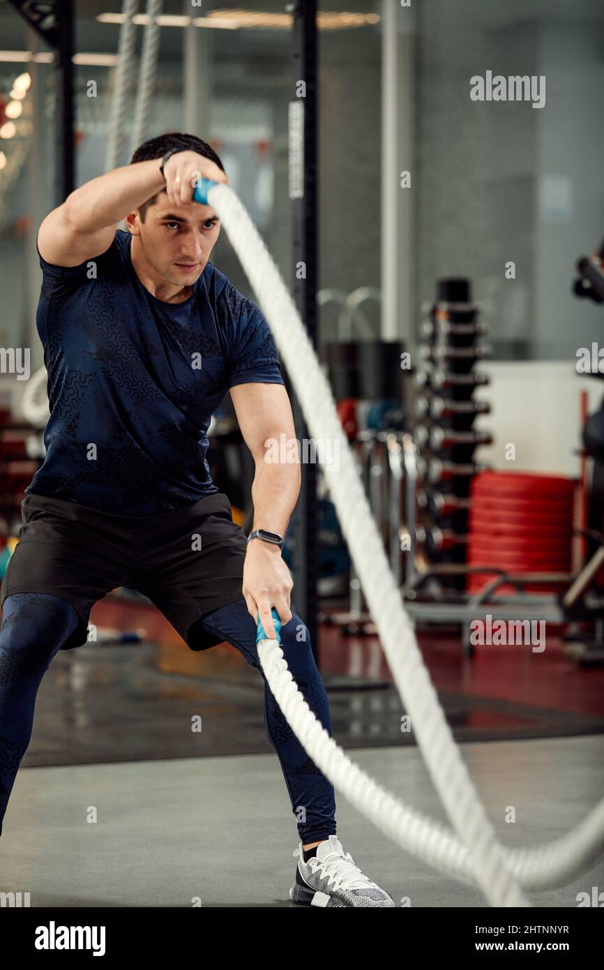Man sitting on his toes holding a pair of battle ropes for workout. guy ...